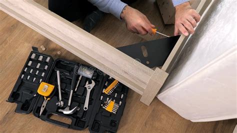 Close Up Of A Man S Hands Assembling A Wooden Bed Using A Screwdriver