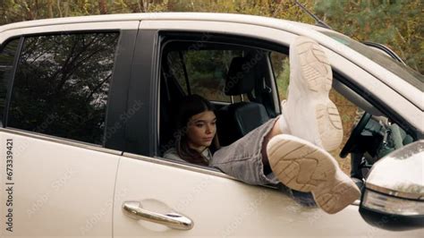 A Girl Sits In The Car In The Front Passenger Seat Stretching Her Legs