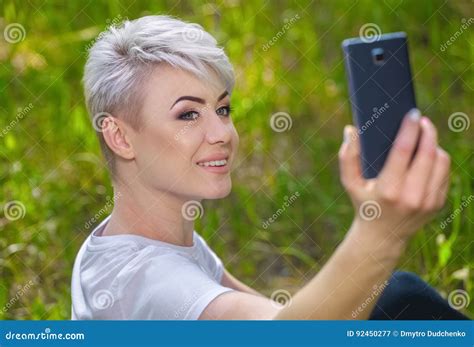Young Attractive Blond Girl With Short Hair Doing Selfie On Nature