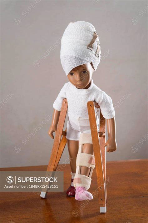 Doll With Bandaged Head Leg Splint Crutches Walking Upright Frontal View Superstock