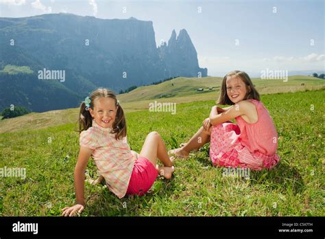 Italy South Tyrol Seiseralmtwo Girls 6 7 10 11 Sitting In Meadow
