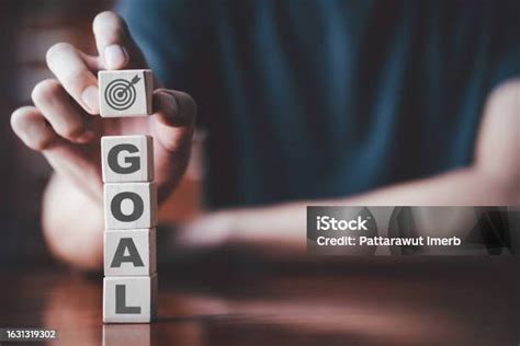 올해 목표와 업적을 설정하고 시작 및 사업 재무 계획 작업 목표 개념을 달성합니다 Goal 큐브 더미에 타겟 보드가 표시된 나무 큐브를 들고 있는 남자 개념에 대한 스톡