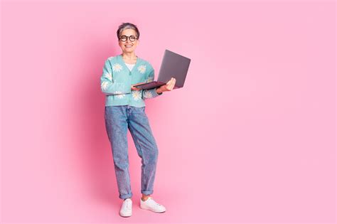 분홍색 배경에 노트북을 들고 쾌활하고 현대적인 라이프 스타일을 보여주는 세련 된 노인 여성 50 54세에 대한 스톡 사진 및