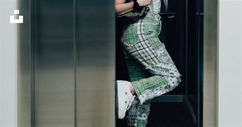 녹색과 흰색 격자 무늬 드레스 셔츠와 회색 벽에 기대어 검은 바지를 입은 여자 사진 Unsplash의 무료 엘리베이터 이미지