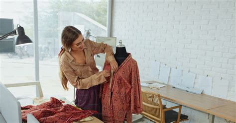 직업 워크샵에서 패션 디자이너 아름다운 여성 재단사는 마네킹에 드레스를 측정하고 스케치북에서 무언가를 기록합니다 성공 자영