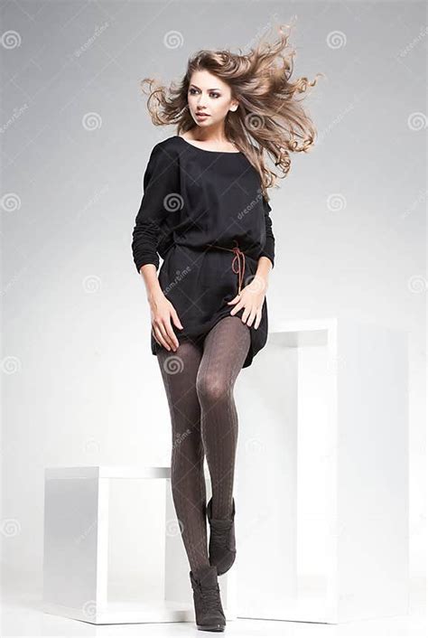 Красивая женщина с длинними сексуальными ногами одела шикарный представлять в студии Стоковое