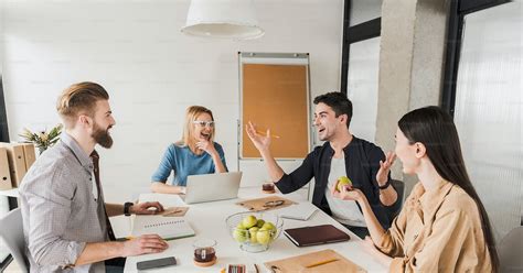 재미있는 관리자들이 프로젝트에 대해 논의하고 있습니다 그들은 직장에 둘러앉아 유쾌한 몸짓을 하는 동료의 말을 듣고 있습니다