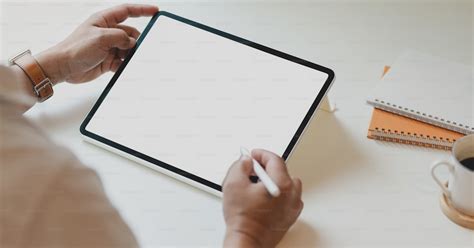 흰색 책상에 사무용품이 있는 최소한의 사무실에서 빈 화면 태블릿을 사용하는 남자 복사 공간이 있는 상위 뷰 사진 Unsplash의 제조 대상 이미지