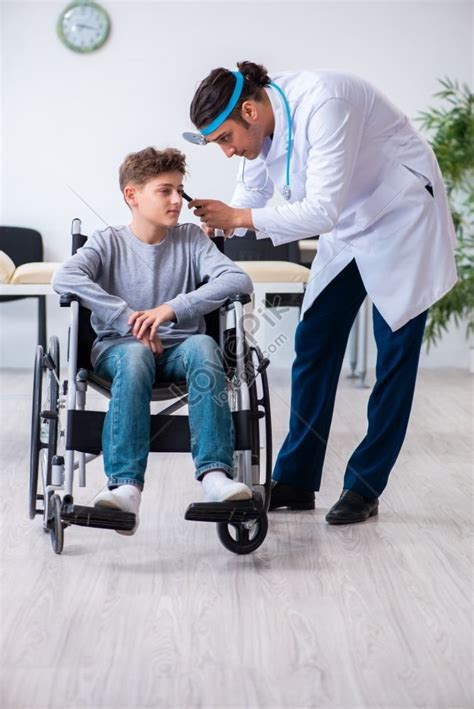 젊은 남성 소아과 의사와 휠체어를 탄 소년 사진