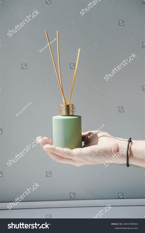 Aroma Diffuser With Incense Sticks In A Bottle In The Male Hand On A Gray Background A Cozy