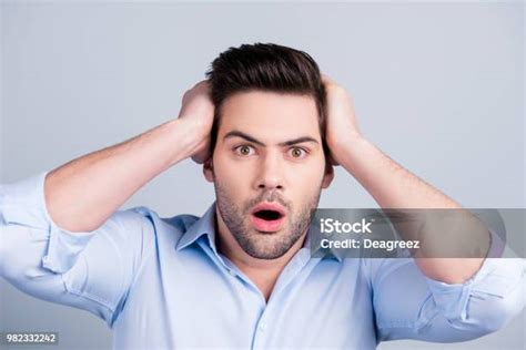 수염과 활짝 열린된 입 셔츠 회색 배경에 고립 된 두 손으로 머리를 만지고 놀된 충격된 남자의 초상화 갈색 머리에 대한 스톡 사진 및 기타 이미지 Istock