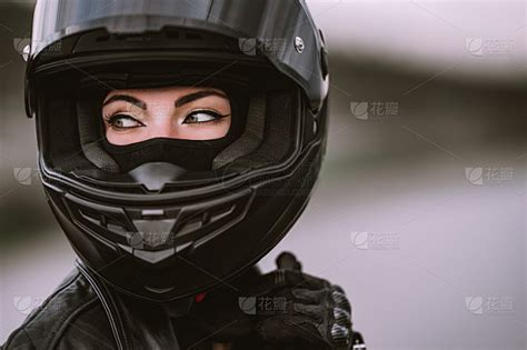 一幅自信的女摩托车手戴着摩托车头盔的肖像。年轻的车手，骑着摩托车，看向外面。咖啡赛车，摩托车美学和复