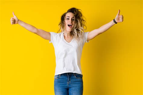 아름 다운 젊은 금발의 여 자가 행복 하 고 흥분 엄지손가락으로 격리 된 노란색 배경 위에 점프 곱슬 머리에 대한 스톡 사진 및 기타 이미지 Istock