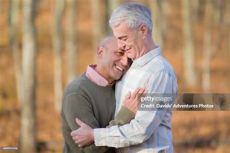 Mature Gay Couple Affectionately Embracing In Wooded Area In An Intimate Moment High Res Stock