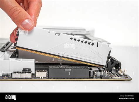 A Person Is Carefully Inserting A White Ddr Ram Module Into A