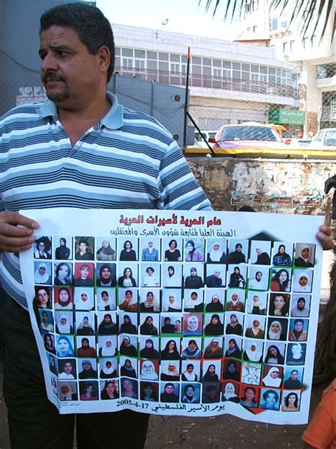 فلسطيني يحمل بوستر يضم صور الاسيرات الفلسطينيات في سجون الاحتلال