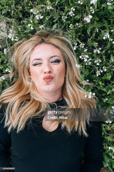 Blonde Woman Winking And Laying In The Grass Surrounded By Daisies High