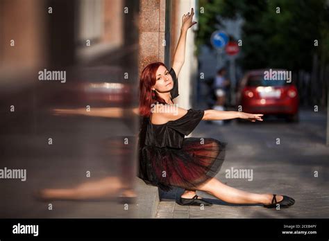 Redhead Ballerina With Black Tutu And Red Ballet Tips Warming Up To Dance On The Street
