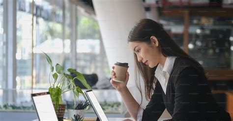 커피 컵을 들고 현대 사무실에서 노트북 컴퓨터로 작업하는 매력적인 사업가의 측면 모습 사진 Unsplash의 측면보기 이미지