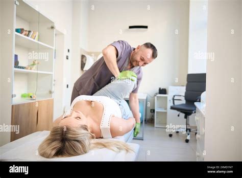 Physiotherapist Testing Woman For Hip Impingement During Physical