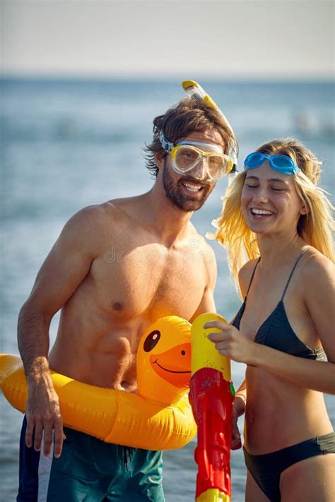 Portrait Shot Of Playful Couple At The Beach Man With Rubber Duck