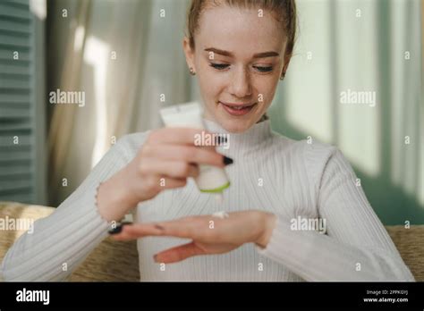 Young Woman Holding Tube And Pouring Cream On Skin Hands Care About