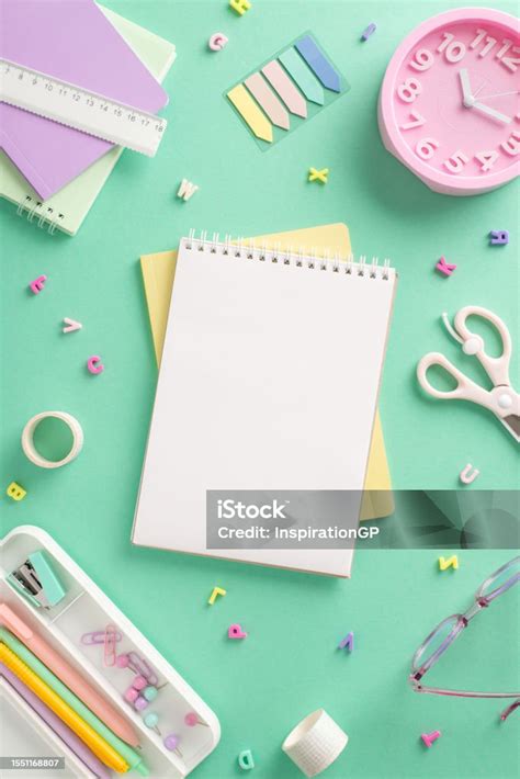 세련된 학용품 배치 일기장 필통 스티커 메모 가위 통치자 분홍색 시계 안경 청록색 배경에 알파벳 문자의 수직 평면도 텍스트