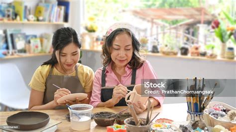 젊은 여성과 은퇴 한 여성은 도자기 작업장에서 굽기 전에 그릇에 그림을 그립니다 25 29세에 대한 스톡 사진 및 기타 이미지 25 29세 2명 55 59세 Istock