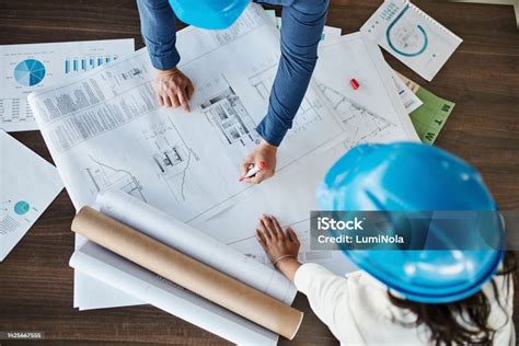 산업 건축가 사무실에서 위의 청사진 용지에 대한 엔지니어 건축 및 설계 계획 전문 리드 빌딩 디자이너 및 관리자가 문서 또는 서류 작업과 전략을 논의합니다 20 24세에