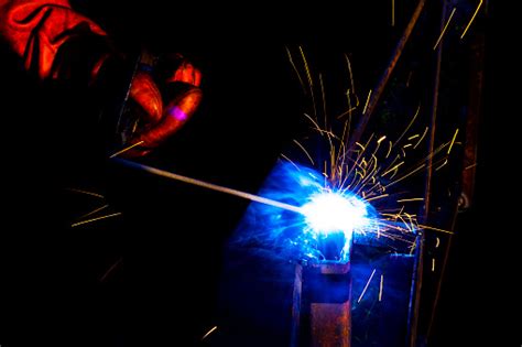 용접기 작업자가 점프 용접을 수행합니다 보호 장갑의 남자 용접기는 금속 구조의 아크 용접 공정을 수행합니다 용접 기에서 불꽃 비행 배경 건설 현장 강철에 대한 스톡 사진 및