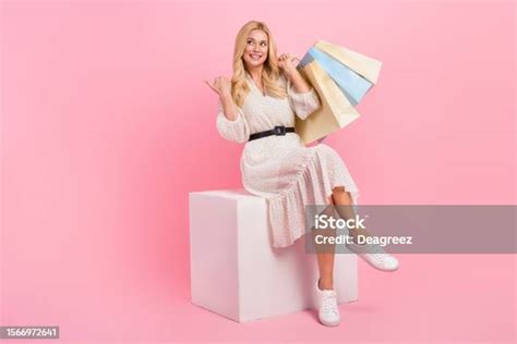 물결 모양의 머리 소녀의 전신 간부는 손가락 모형을 지시하는 흰색 상자에 앉아 분홍색 배경 위에 격리된 새로운 구찌 매장 할인 가방에 대한 스톡 사진 및 기타 이미지