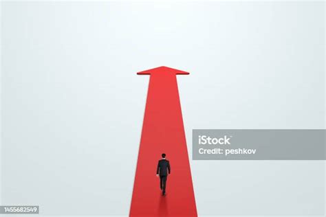 성공 성취 및 개인 개발 개념으로 가는 길은 밝은 배경에서 사업가의 뒷모습을 키우는 화살표의 형태로 레드 카펫을 걷고 있습니다 청년 성인에 대한 스톡 사진 및 기타 이미지