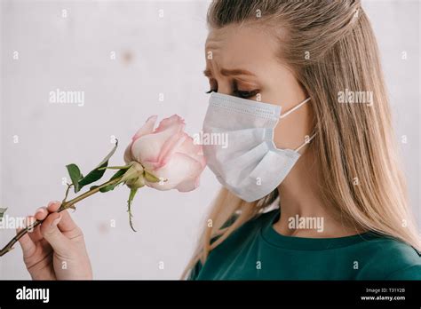 Blonde Woman With Pollen Allergy Wearing Medical Mask And Smelling Rose Stock Photo Alamy