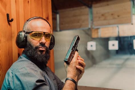 A Man Practices Shooting A Pistol In A Shooting Range While Wearing