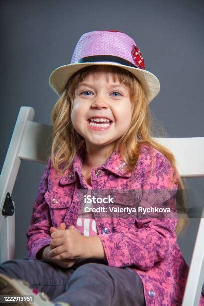 모자를 쓴 어린 소녀 미소와 웃음 회색 배경 핑크 셔츠와 회색 바지 어린 시절은 유쾌하게 전달됩니다 건강한 생활방식에 대한 스톡