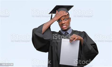 젊은 흑인 남자 머리 수치심과 깜짝 얼굴로 충격된에 손으로 압박 고립 된 배경 위에 빈 종이 들고 졸업 분노와 좌절 두려워 하 고 실수에 대 한 화가 대학교에 대한 스톡
