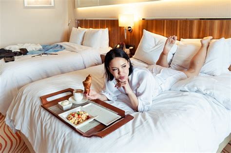 목욕 가운을 입고 호텔에서 커피와 크로와상으로 아침 식사를 하는 침대에 누워 있는 어두운 피부의 젊은 여성 먹기에 대한 스톡 사진 및 기타 이미지 Istock