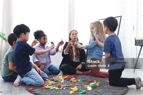 초등학생 그룹은 교사와 함께 교실에서 함께 공부하고 놀고 다양한 학생들이 활동을 하는 동안 바닥에 앉아 재미있고 어린이 교육 다양성 및 다양성 교실을 가지고 있습니다 교육에