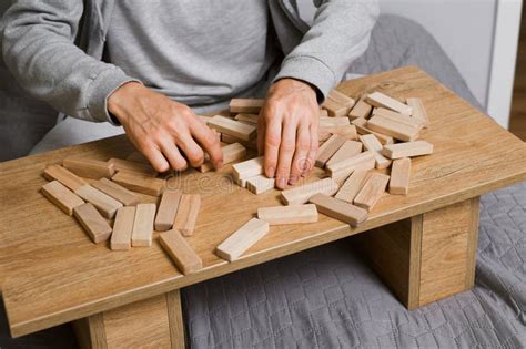 Man Carefully Stacking Wooden Blocks In A Game Of Skill At Home Stock