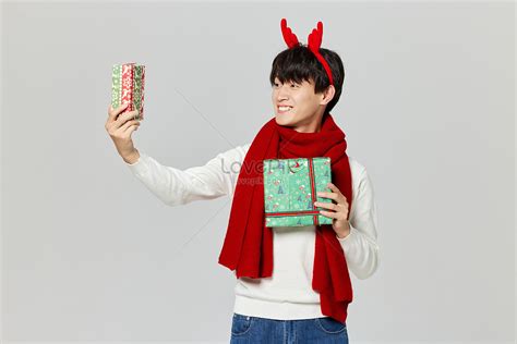 젊은 남자가 크리스마스 선물을 손에 들고 있다 사진 무료 다운로드 Lovepik