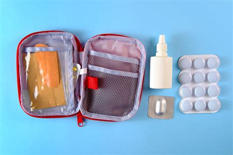 밝은 파란색 배경에 알약 접착제 붕대 및 비강 스프레이 근처의 빨간색 관광 응급 처치 키트 파우치 를 열었습니다 0명에 대한 스톡 사진 및 기타 이미지 Istock