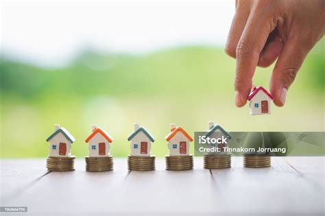동전 스택에 집 모델을 넣어 여자의 손 부동산 사다리에 대한 개념 주택에 대한 주택 개념 부동산 모기지 및 투자를 구입하는