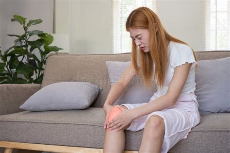 Asian Woman Experiencing Knee Pain At Home Concept Of Joint Discomfort