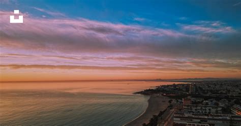 도시를 배경으로 한 해변의 일몰 사진 Unsplash의 무료 토레 데 라 호라다다 이미지