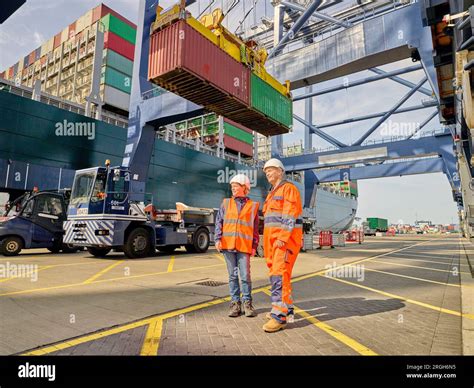 Dock Workers By Crane Lowering Cargo Container Onto Truck Stock Photo Alamy