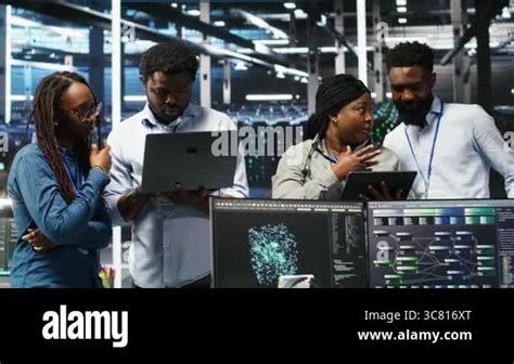 portrait of smiling data center specialists collaborating in server facility using node tree