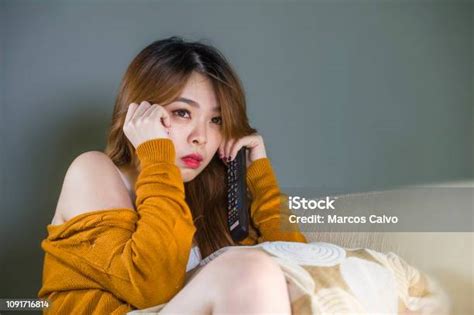젊은 매력적이 고 귀여운 무서 워 아시아 한국 여자 보고 공포 영화 또는 Tv 드라마 지주 리모컨 두려움과 공황 얼굴 표현에 집 거실 소파에서 혼자 Brand Name