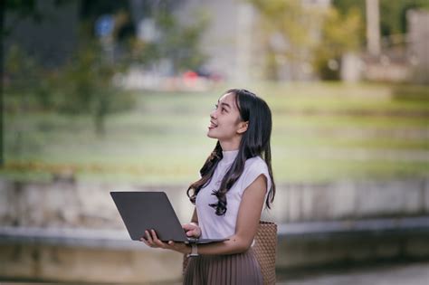 공원에서 노트북으로 작업하며 위를 바라보며 미소 짓고 신선한 공기와 활기찬 자연 환경을 즐기며 야외에서 일과 삶의 균형을