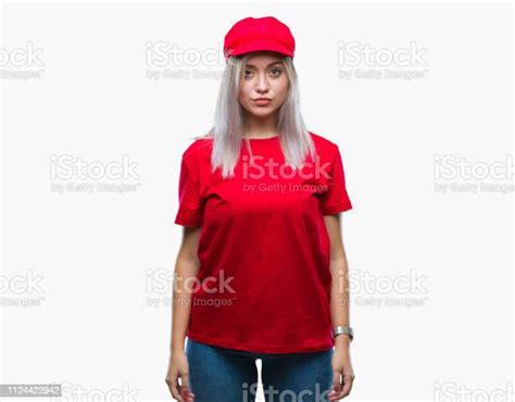 젊은 금발 여자 얼굴에 심각한 표정으로 격리 된 배경 위에 빨간 모자를 쓰고 간단 하 고 카메라를 보고 자연 결심에 대한 스톡