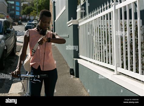 Woman Checking Time On Her Smartwatch While Walking On A Sidewalk Stock